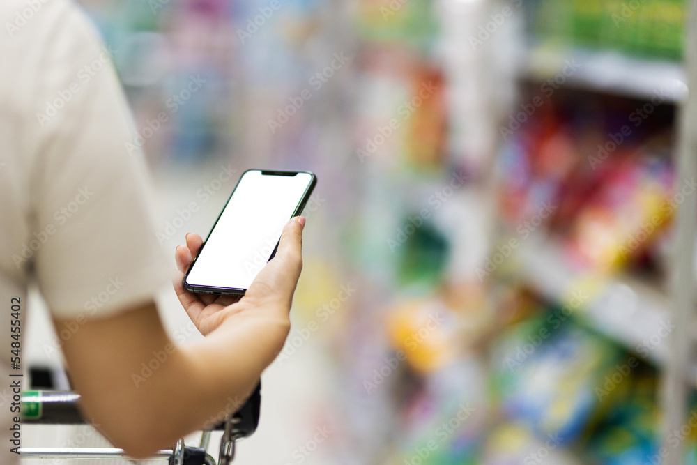 Personal perspective of woman's hand holding a smartphone while grocery ...