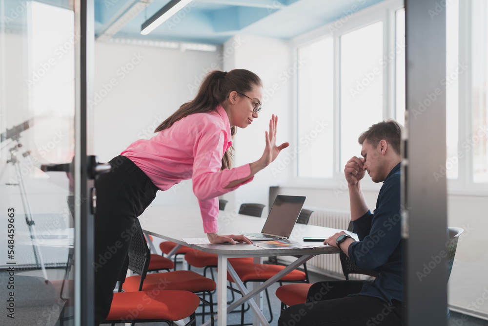 Emotional couple of young colleagues arguing in modern office. Business ...