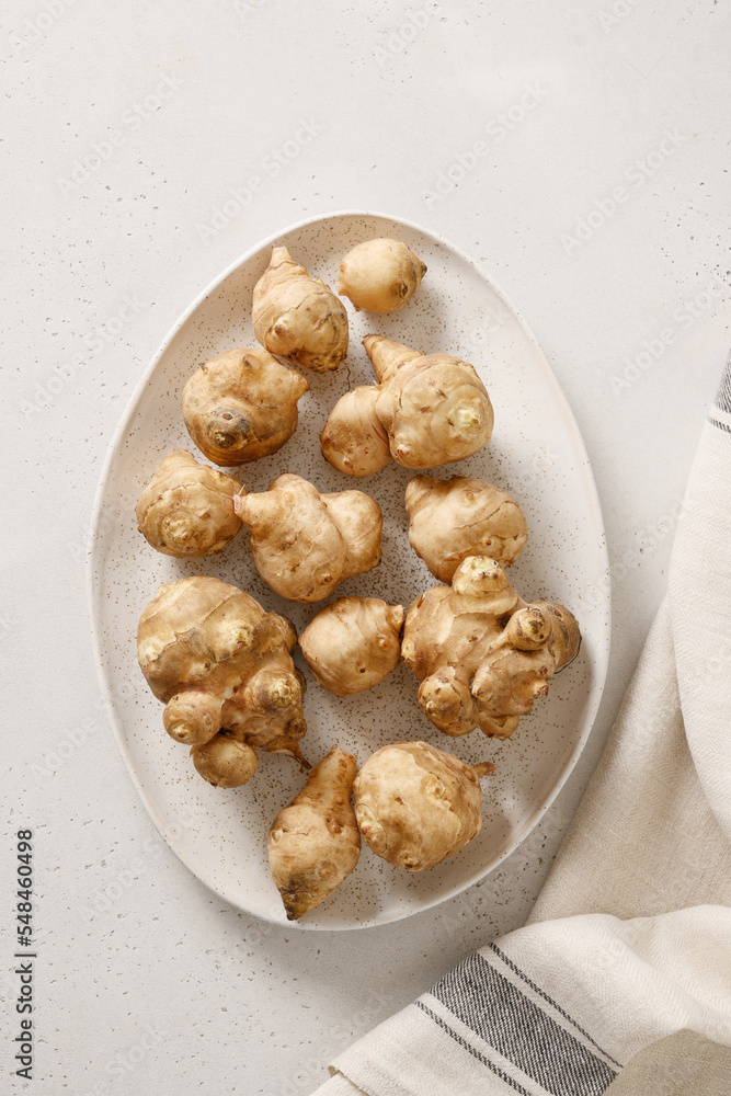 Jerusalem artichoke root, sunchokes in white plate and on white ...