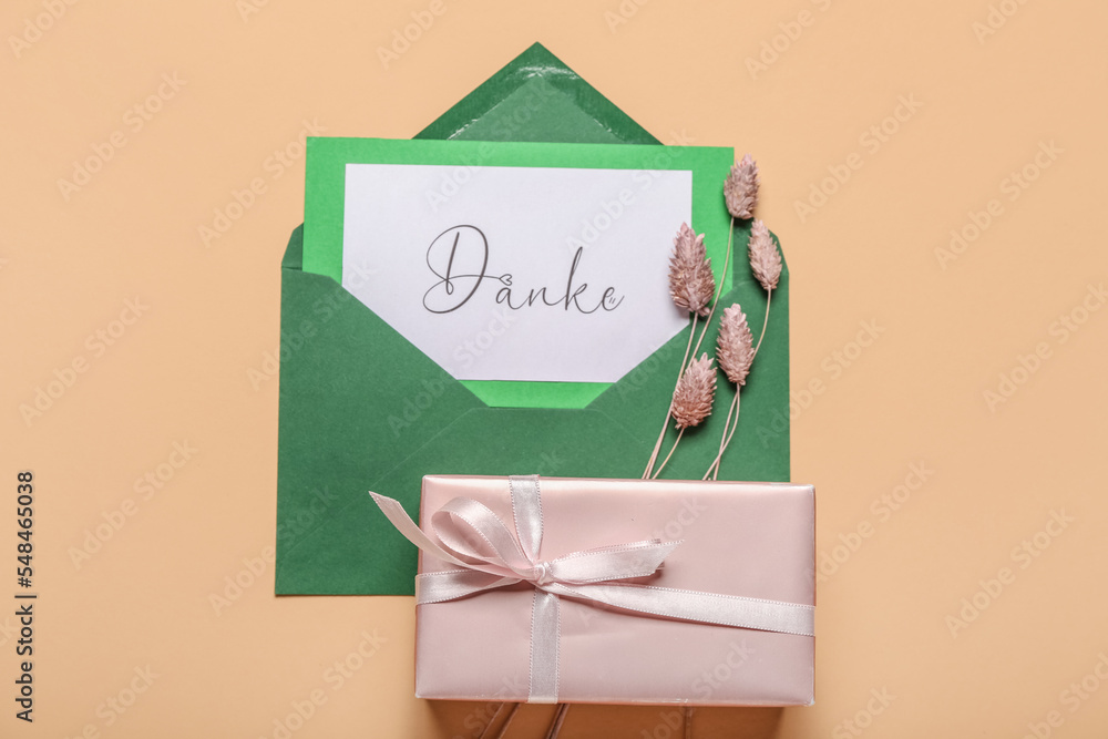 Card with word DANKE, envelope, pampas grass and gift box on beige ...