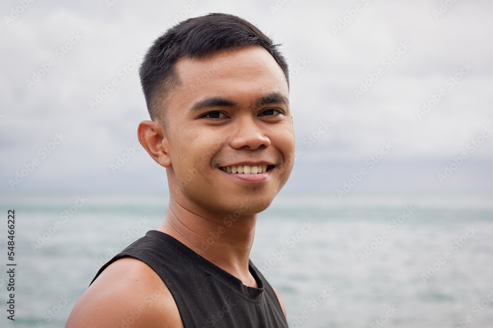 Smiling Portrait Of Young Filipino Man By The Sea On Cloudy Day Asian Male Model Concept Stock