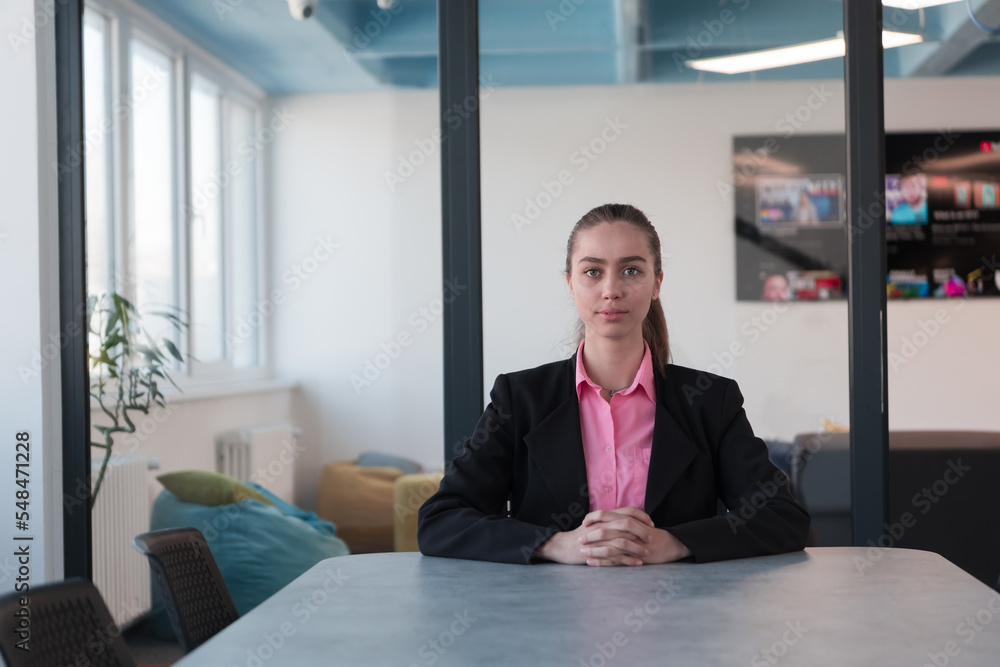 Successful young female leader in a suit with a pink shirt sitting in a ...