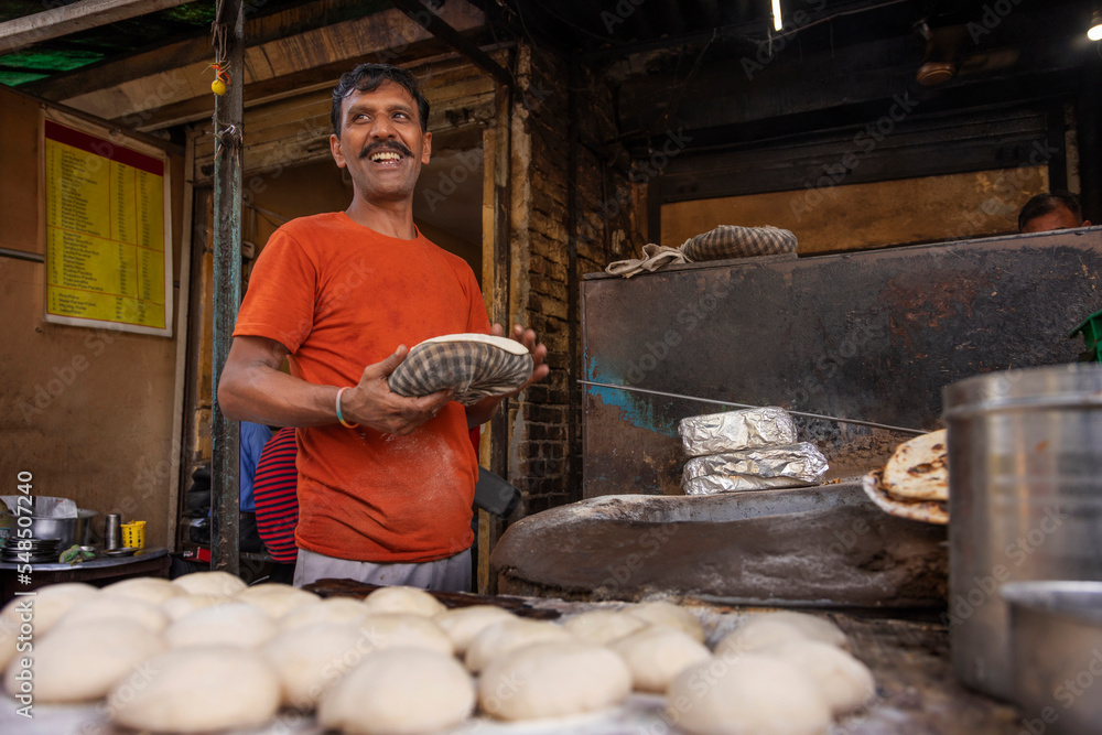 Cook of a local roadside restaurant or a dhaba, making bread or a roti ...