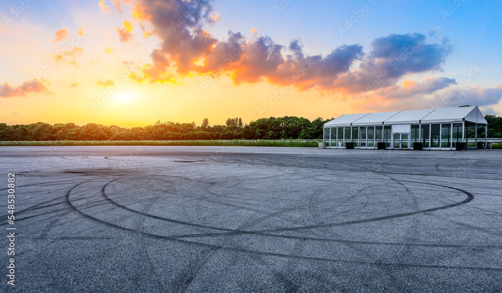 Asphalt race track road and green forest with sky clouds at sunset ...