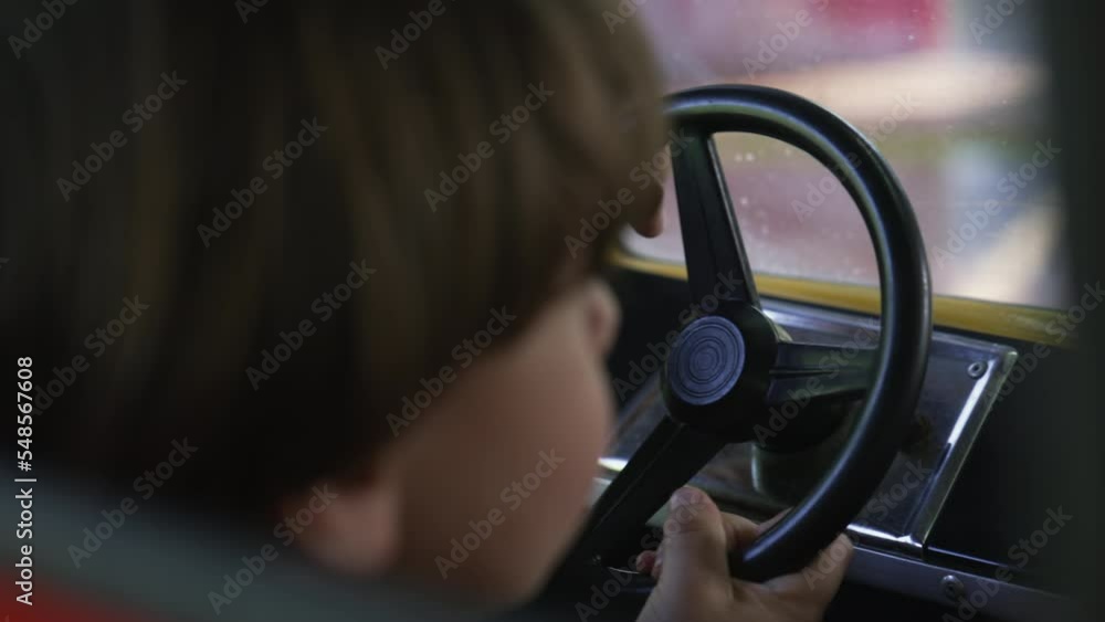 Child pretending to drive inside carousel at amusement park. Small boy ...