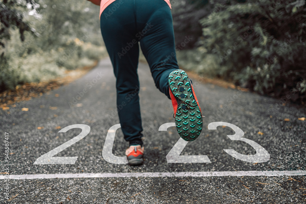 Numbers 2023 written on the road towards new goals in 2023 and female ...
