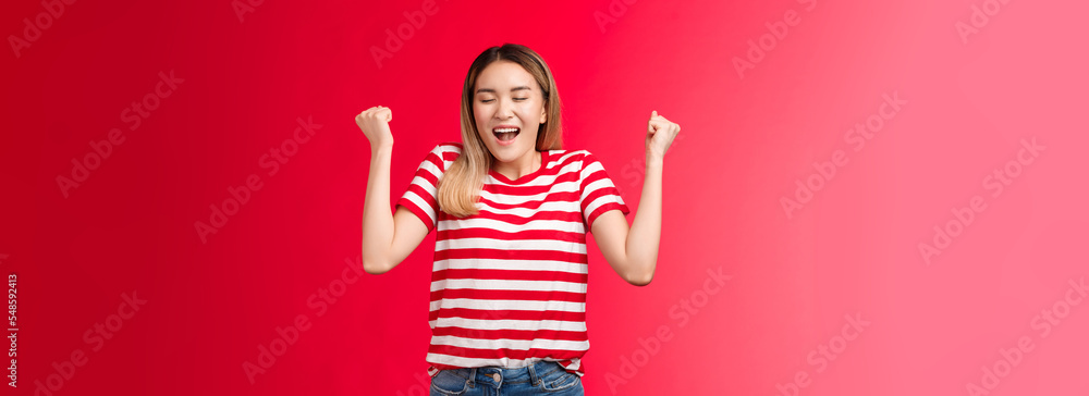 Hooray I did it. Triumphing cute cheerful asian blond girl make fist ...