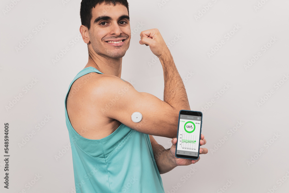 A young man shows his mobile with a continuous glucose monitor blood ...