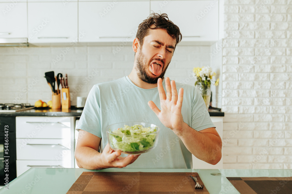 Young guy man hold a salad in his hand, the other pushes him away, you ...
