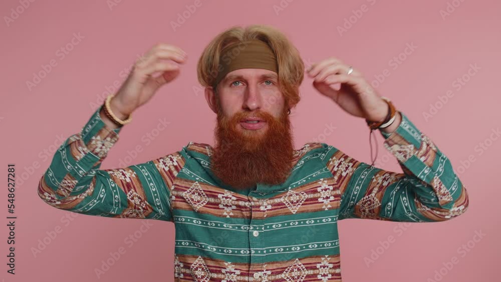 Excited amazed hippie man in pattern shirt touching head and showing ...