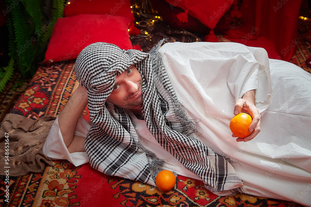 Arab sheikh in a white robe and a headscarf in a boudoir in a room with ...