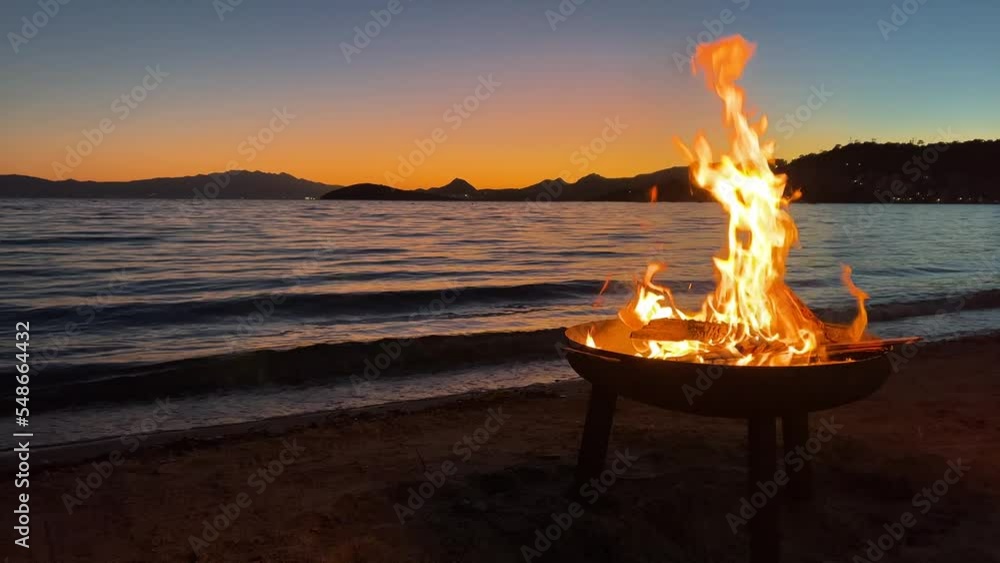 Burning fire pit at beach. Beautiful sunset and sea view with sparkling ...