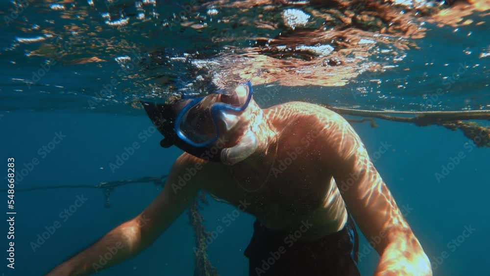 A sporty freediver in blue mask with snorkel underwater is fooling ...