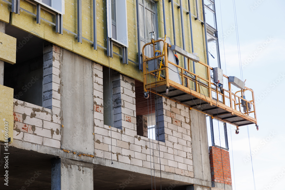 Suspended platform, construction cradle hangs on the building with ...