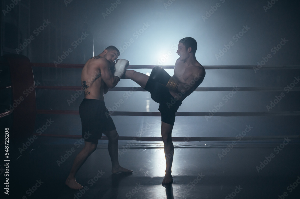 Two shirtless muscular man fighting Kick boxing combat in boxing ring ...