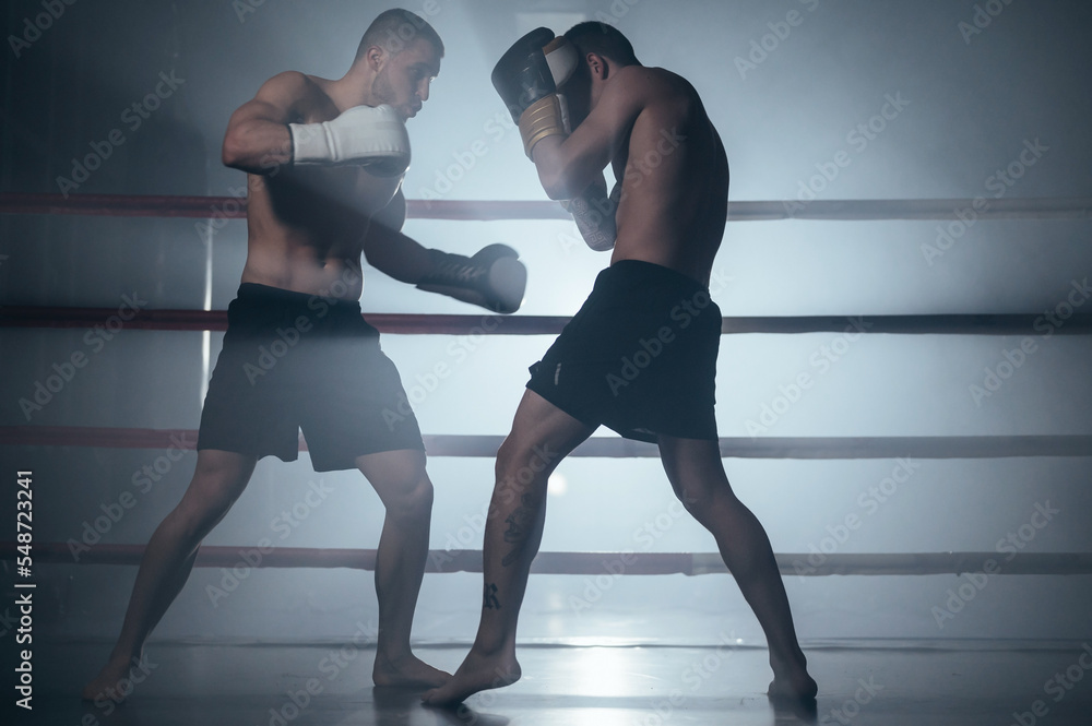 Two shirtless muscular man fighting Kick boxing combat in boxing ring ...