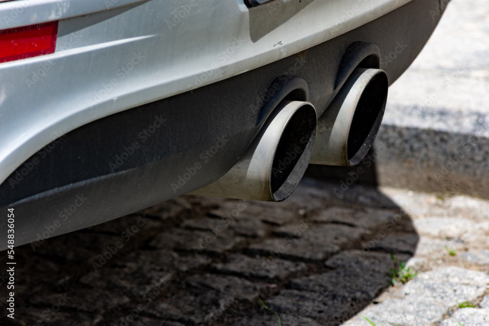 Double exhaust pipe of a modern sport car parked on a road with ...