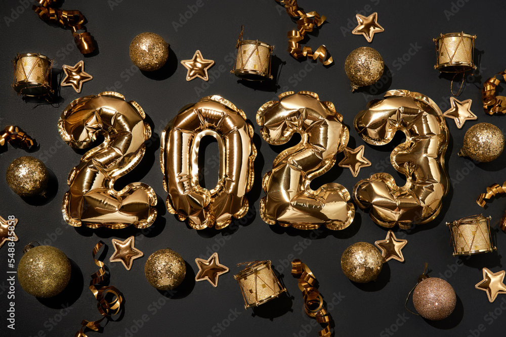 Foil gold air balloons in the form of number 2023 on black background ...