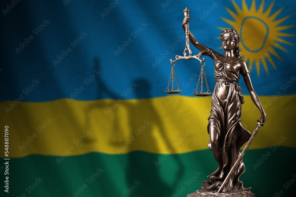 Rwanda flag with statue of lady justice and judicial scales in dark ...