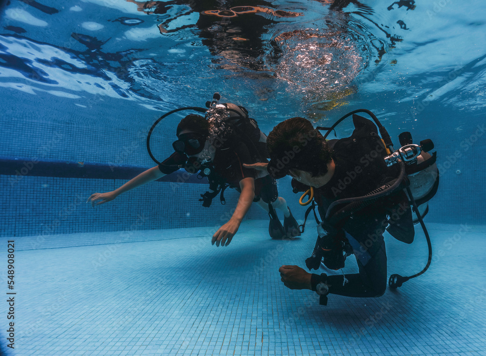 diving instructor teaches students to scuba dive in swimming pool ...