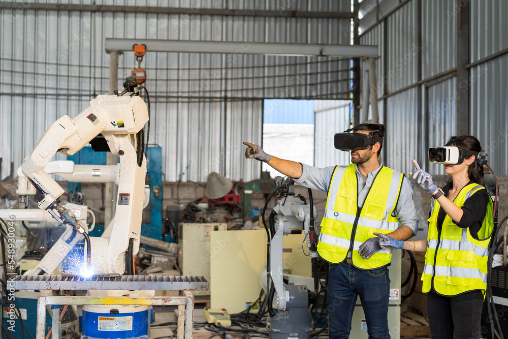 Male engineer and female working control robot arm system welding with ...