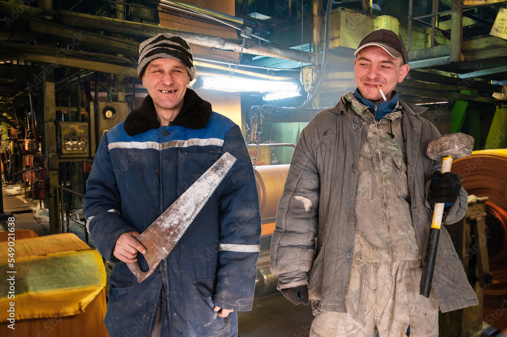 Foto de Two bad unskilled workers in bad dirty tattered uniform with ...