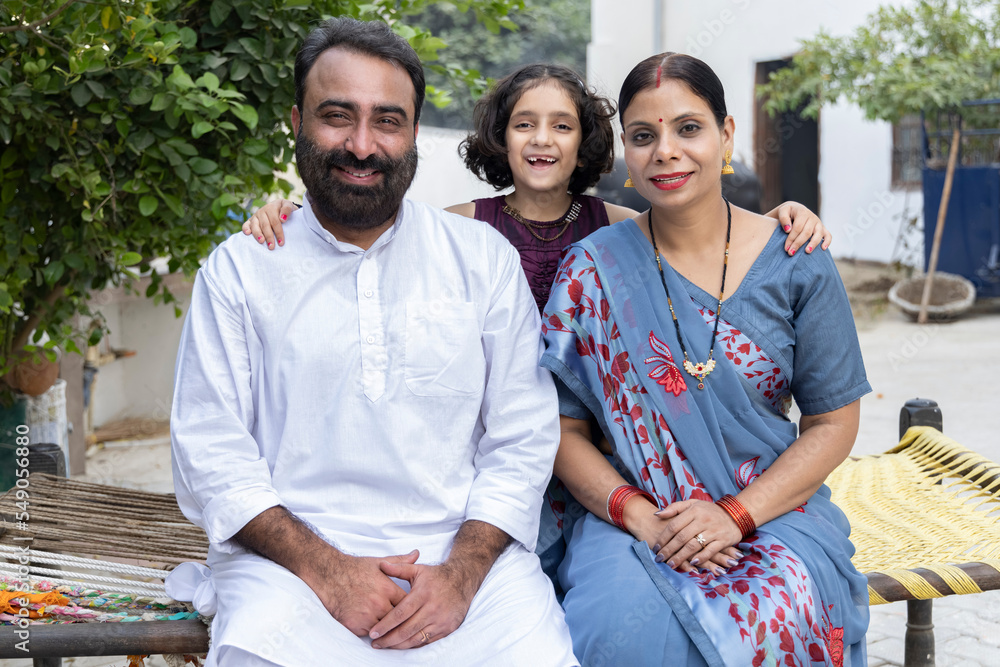 Cheerful rural indian family sitting on traditional bed at village home ...