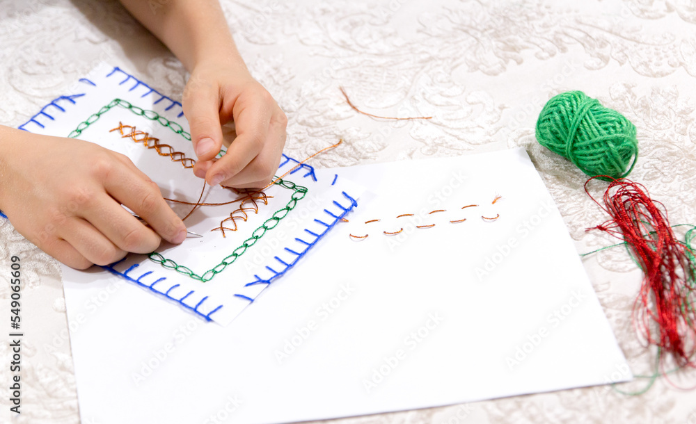 The closeup of hands sewing a colorful card during school activities ...