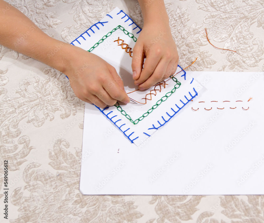 The closeup of hands sewing a colorful card during school activities ...