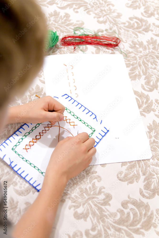 The closeup of hands sewing a colorful card during school activities ...
