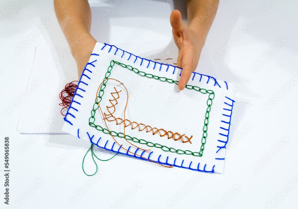 The closeup of hands sewing a colorful card during school activities ...