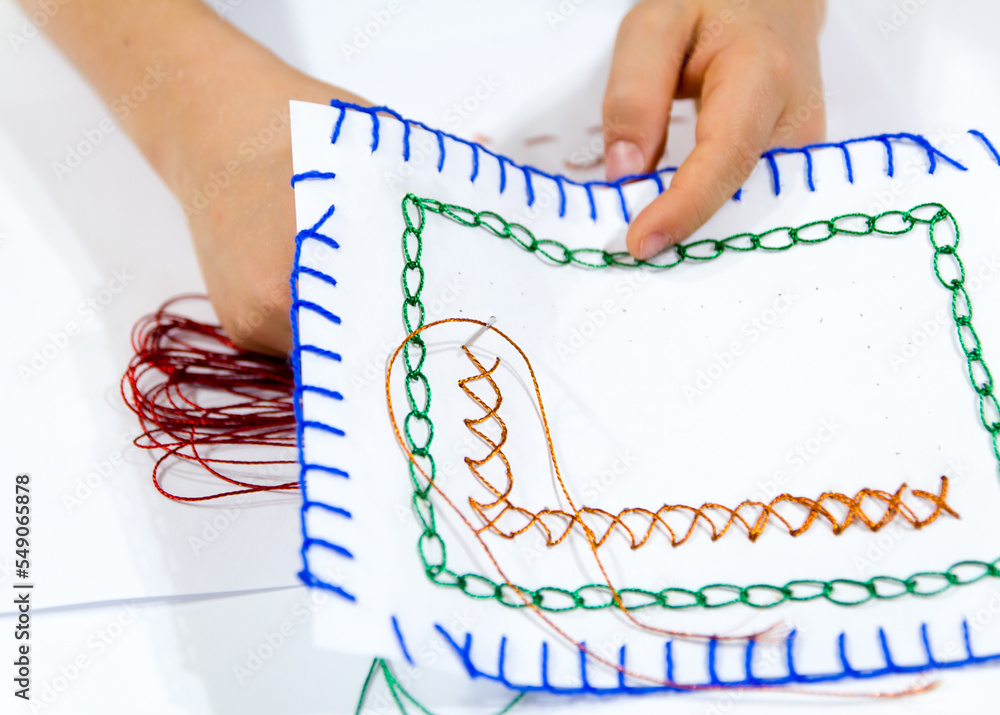 The closeup of hands sewing a colorful card during school activities ...