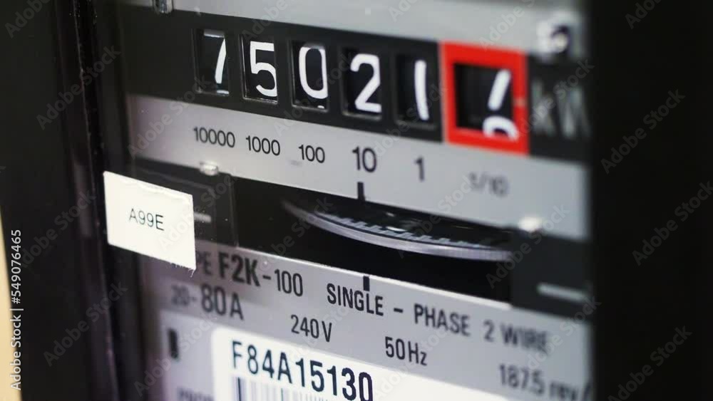 A close-up of an electric meter and number dials. A fast turning rotor ...