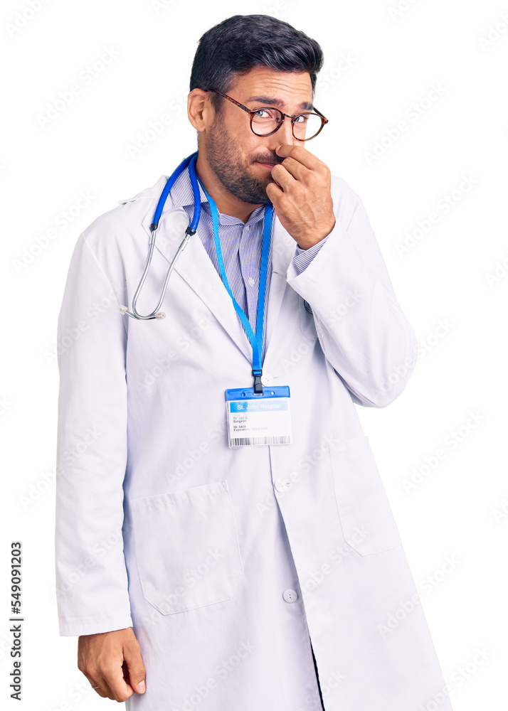Young hispanic man wearing doctor uniform and stethoscope smelling ...
