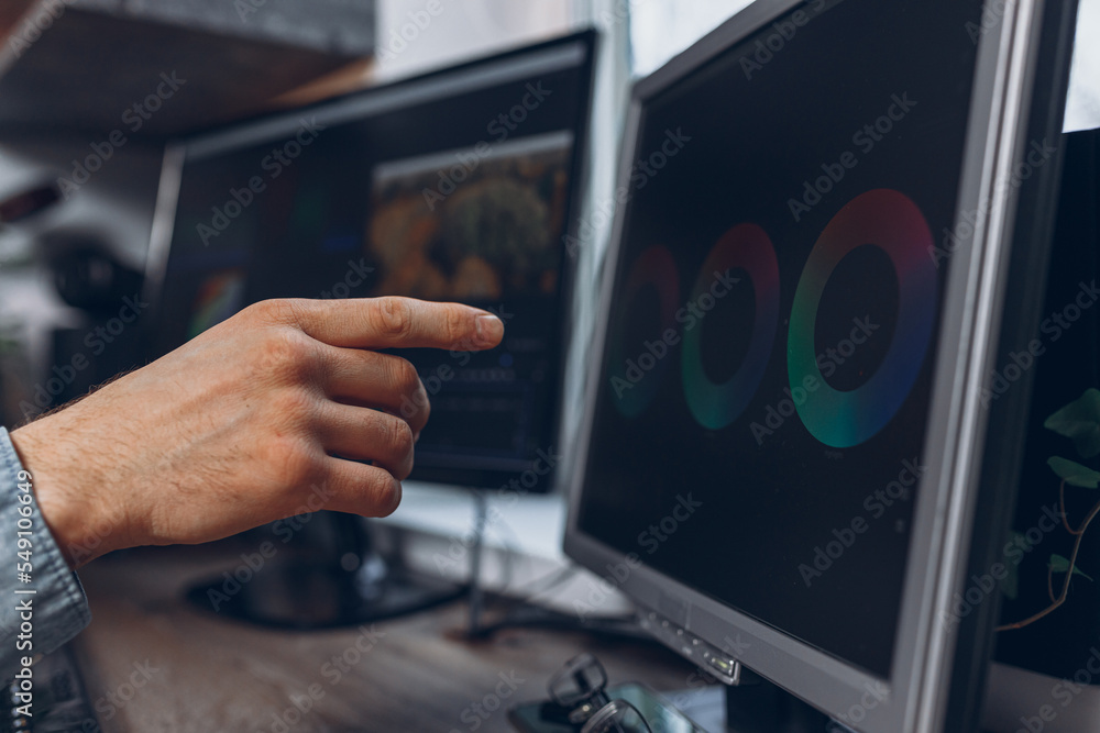 Crop male video editor pointing at desktop computer monitor while ...