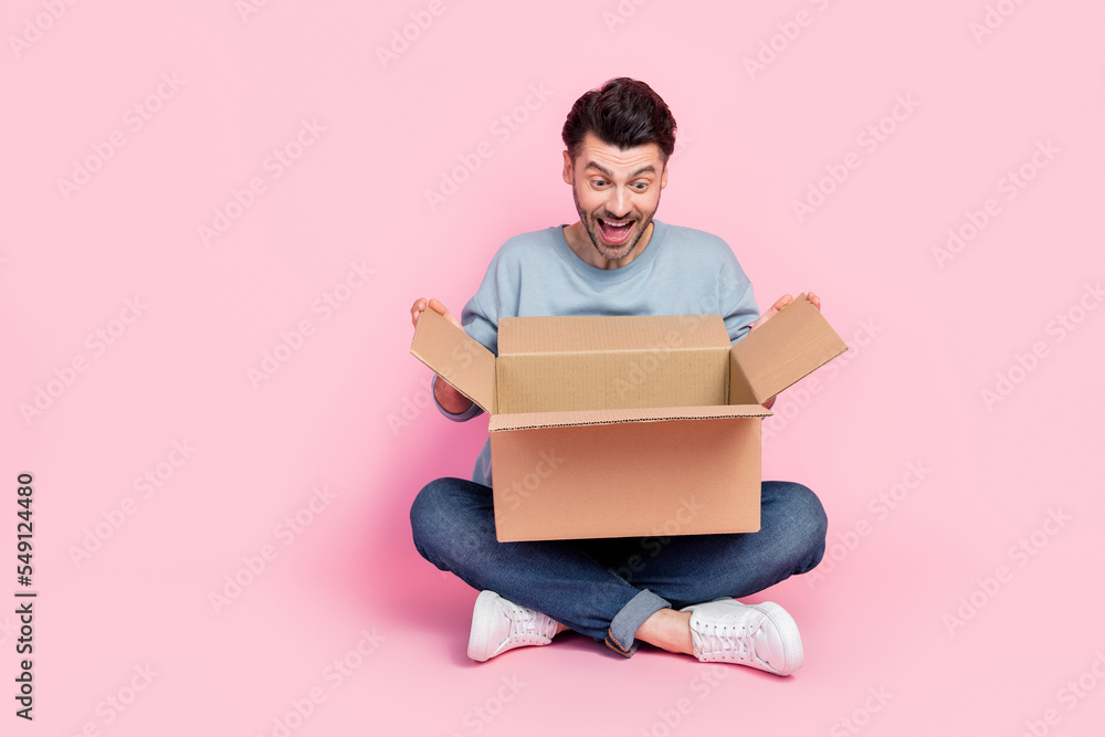 Full size photo of handsome young guy opening carton box excited peek ...