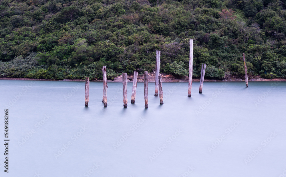 Upright wooden poles left to rot in the sea. Long exposure gives silky ...