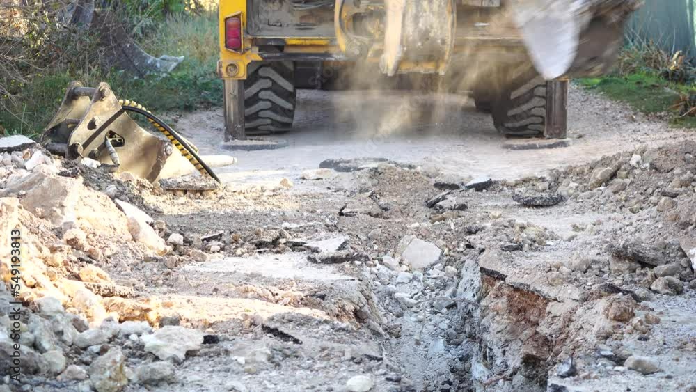 Excavator loudly digs a trench to lay pipes. Close up of an excavator ...