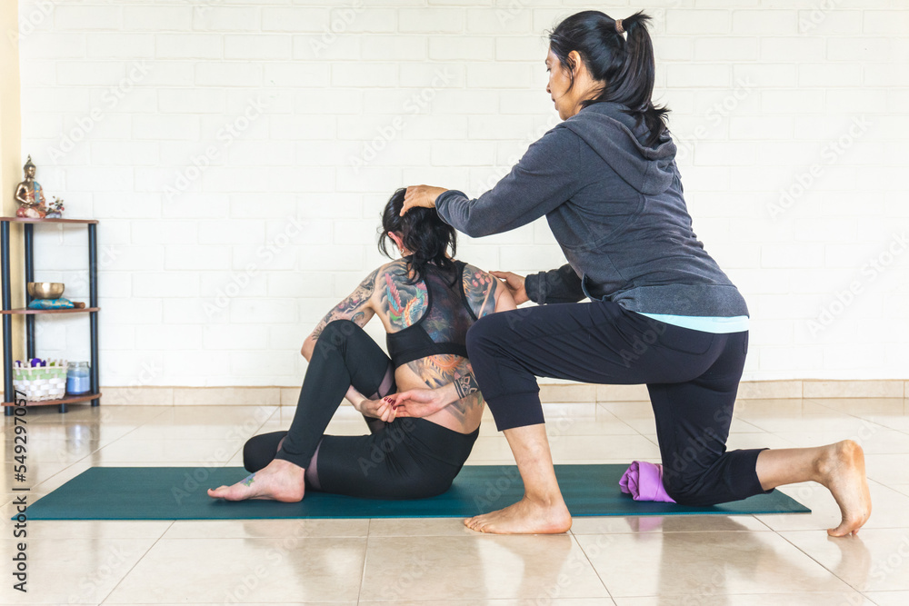 Yoga instructor correcting posture of a student doing ardha ...
