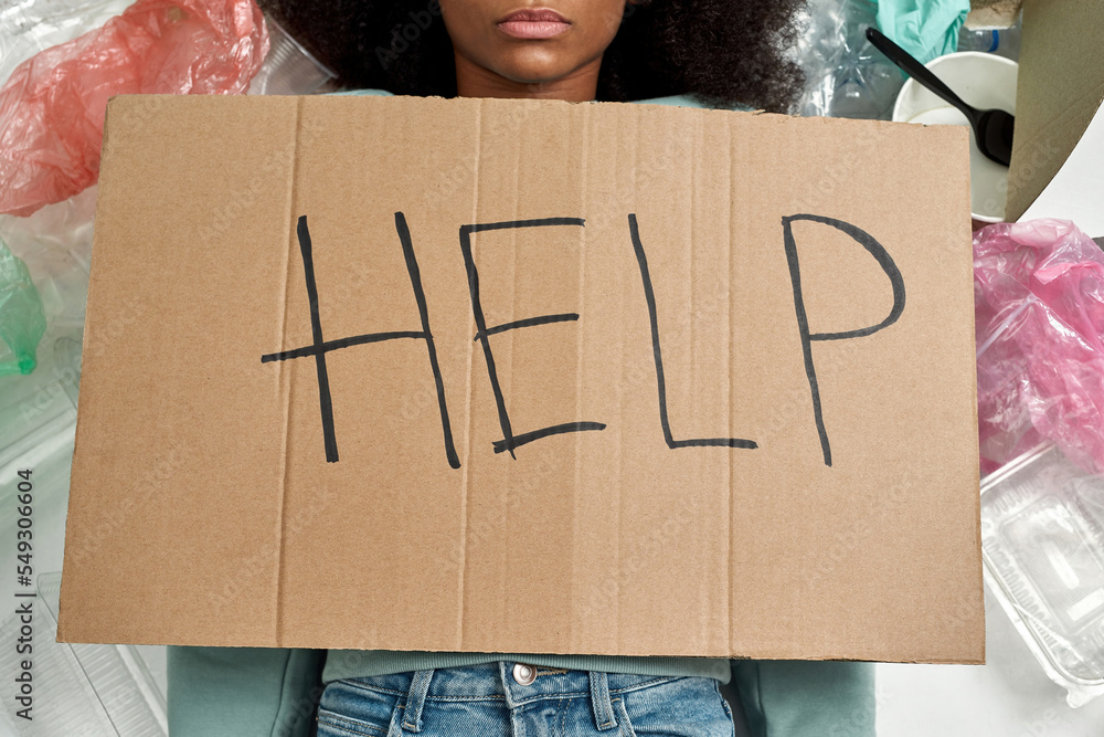 Partial girl and 'Help' placard lying in garbage Stock Photo | Adobe Stock