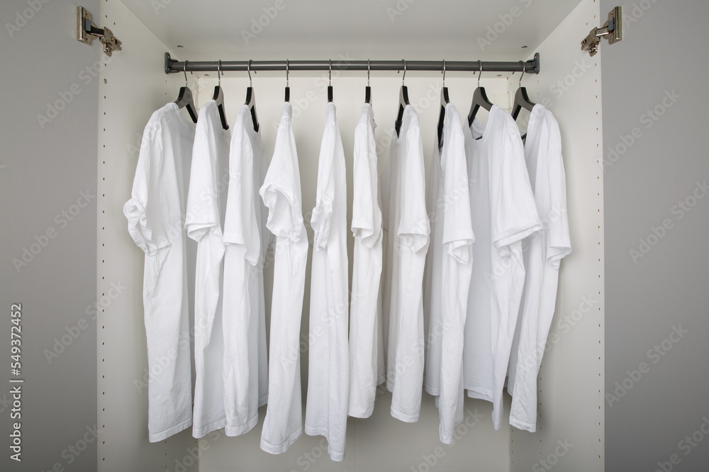 white t-shirts hang on a clothes rail in a white wardrobe. all t-shirts ...
