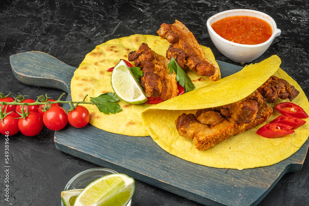 Appetizer of fried pork belly, crispy skin, tortillas, limes, peppers ...