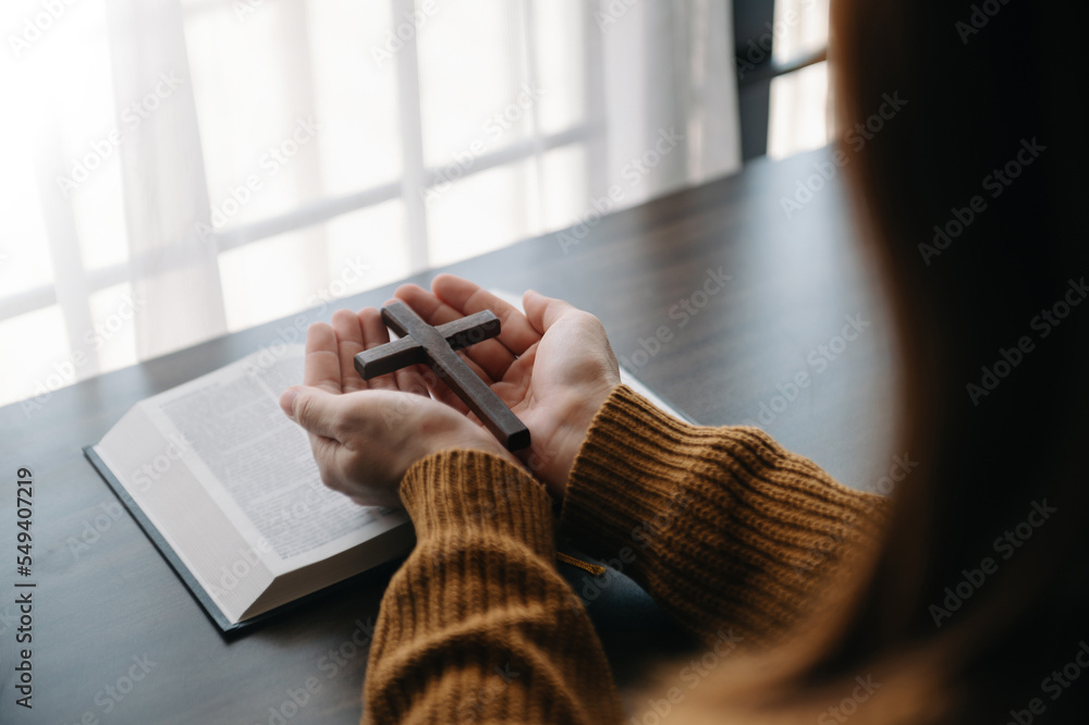 Woman sitting and studying the scriptures.The wooden cross in the hands ...