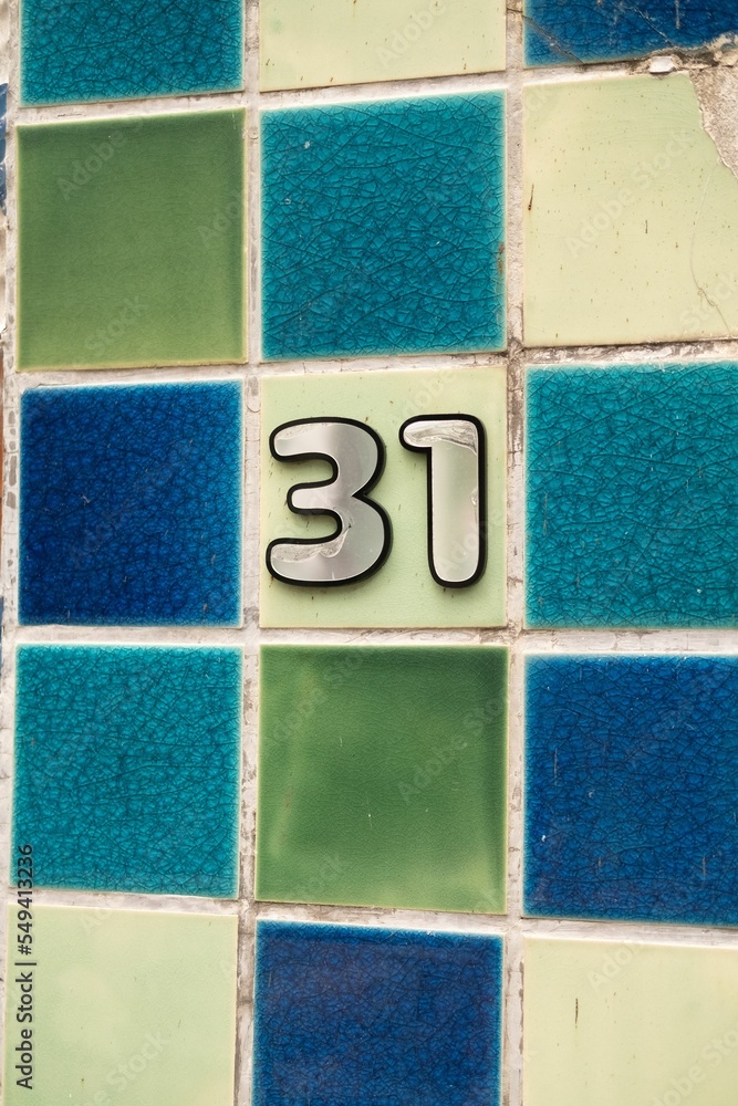 Vertical closeup of plaque plate number address of "31" house on blue ...