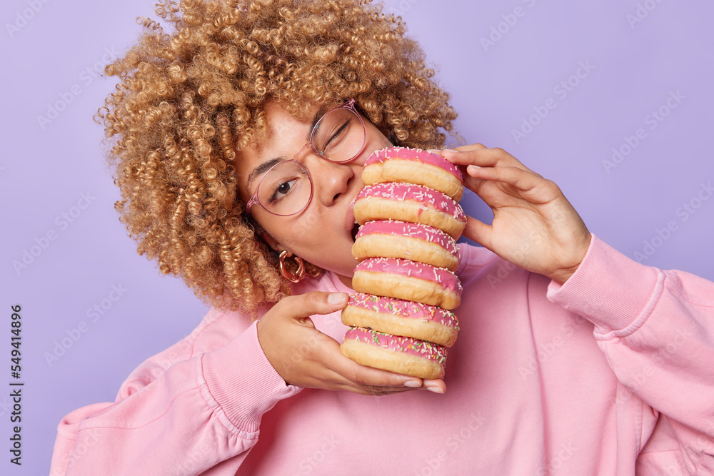 Fotka „Lovely curly haired woman winks eye and eats delicious sweet ...