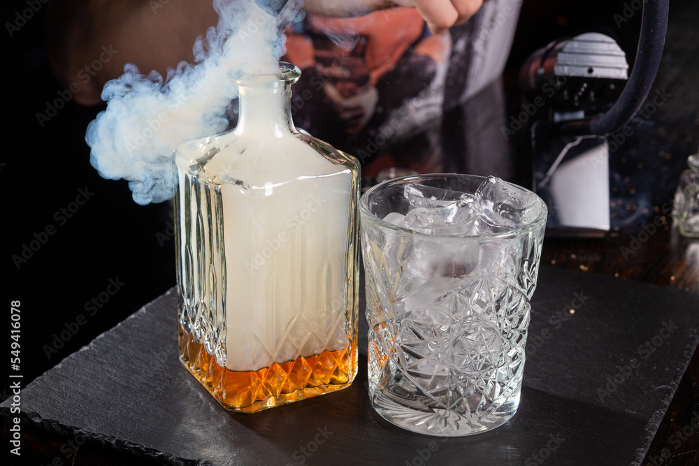 The bartender mixes whiskey with smoke to give a special taste to the ...