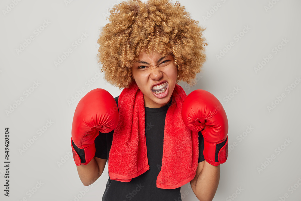 Foto de Displeased female boxer ready for fight wears black t shirt and ...