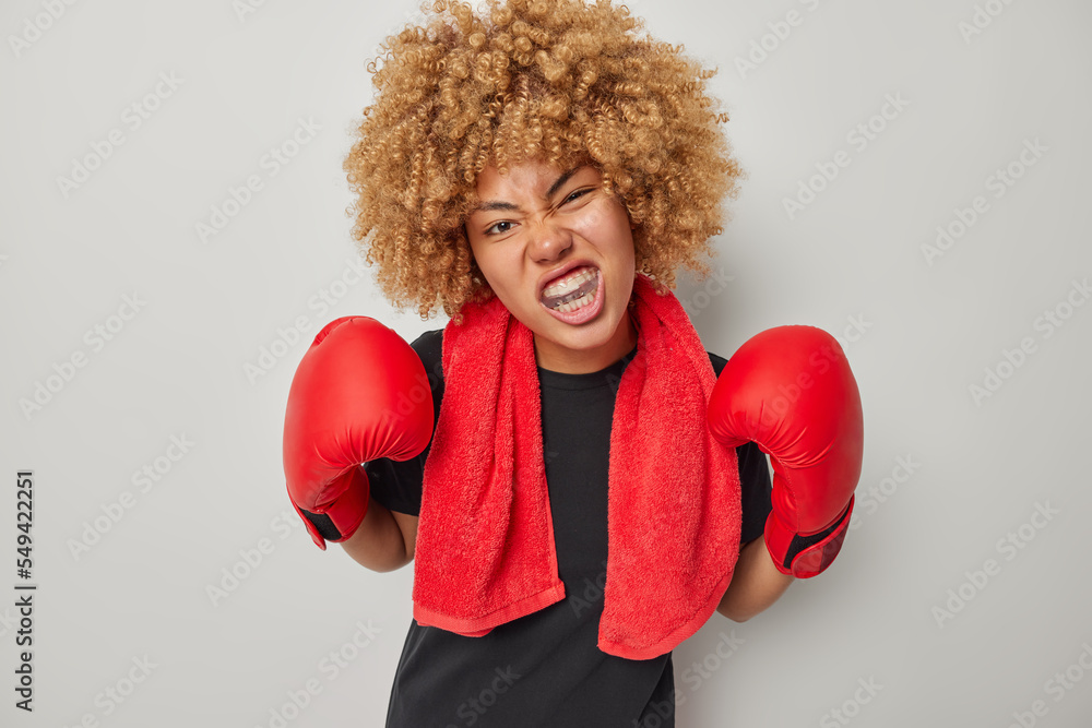 Angry irritated curly female boxer attends self defence classes wears ...