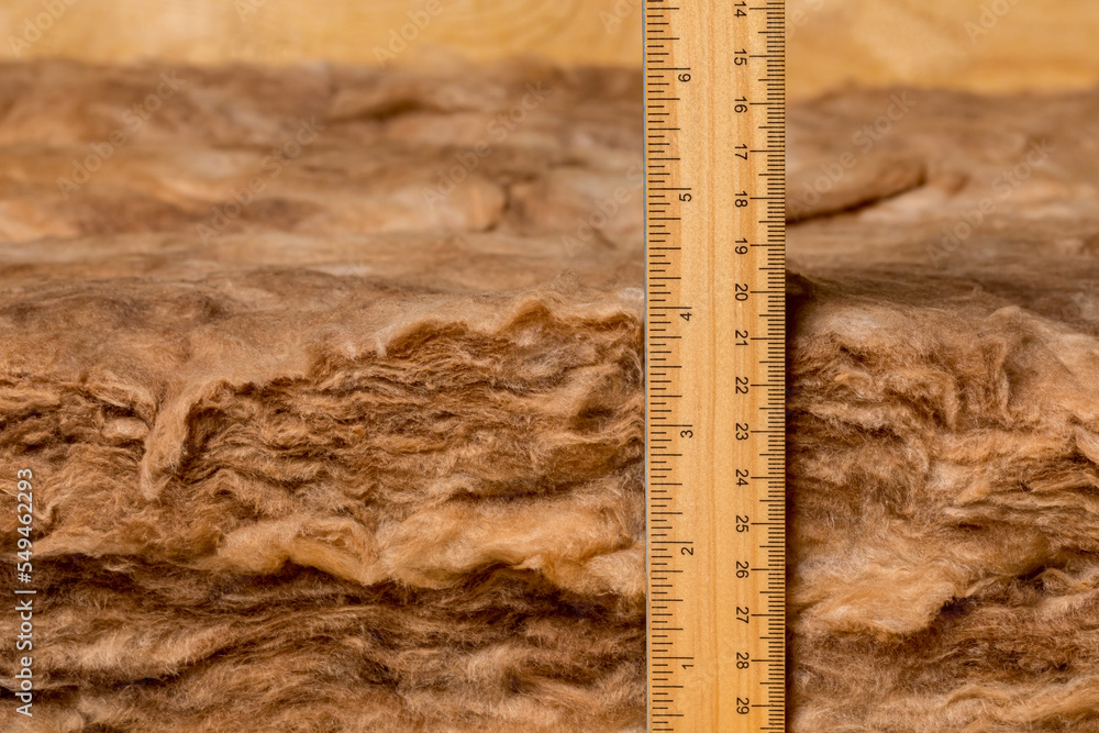 Measuring fiberglass insulation in attic of house with ruler. Home ...