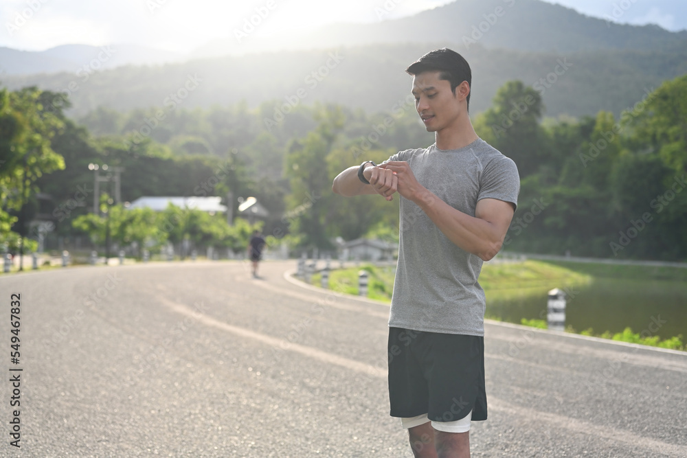 Young Asian athlete man using smartwatch to monitor his activity and ...